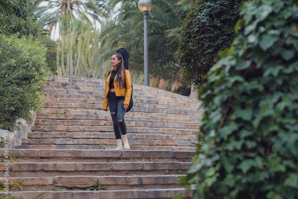 Woman walking down steps with a guitar on her back in a park Stock ...