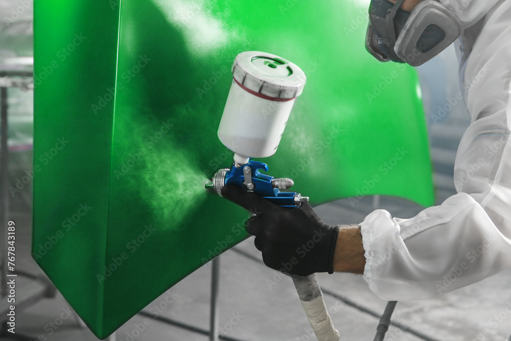 Car paint worker spraying green paint to car body element using spray ...