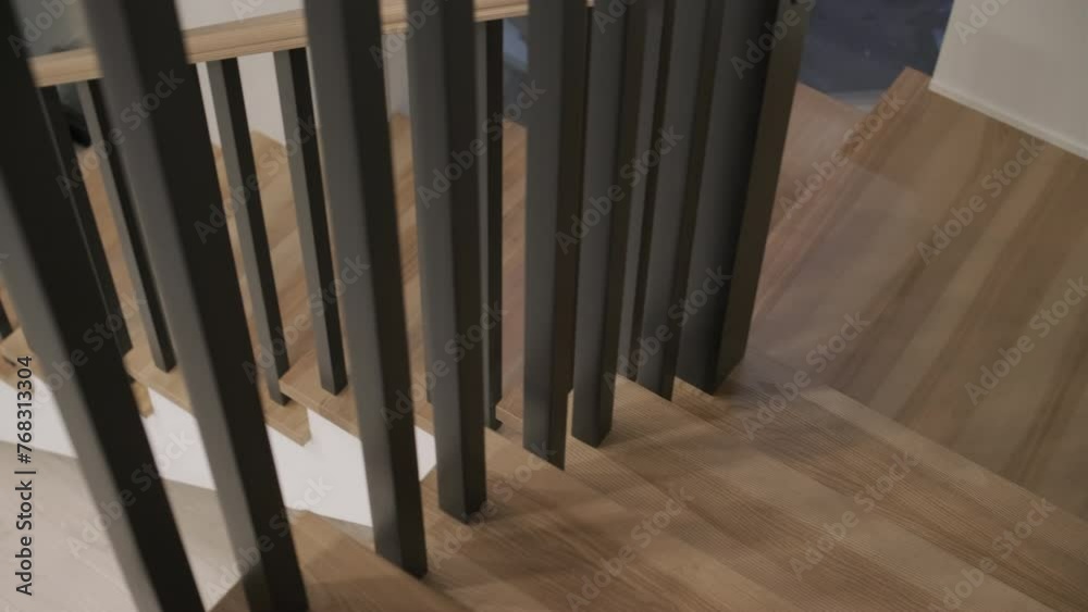 A top-down view of modern wooden stairs with black vertical balusters ...