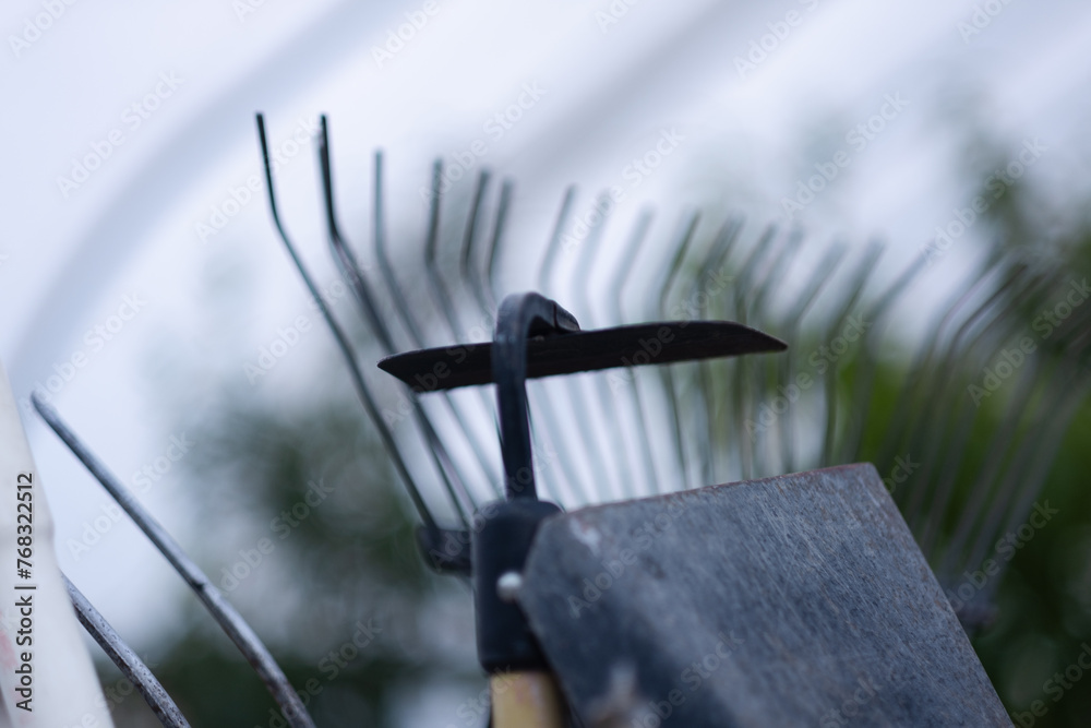 Gardening tools in a greenhouse: a hoe, a shovel, and a rake are placed ...