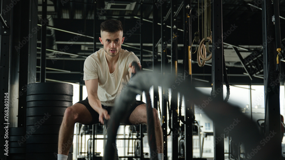 Active man training with battle ropes waves in gym bodybuilding muscle ...