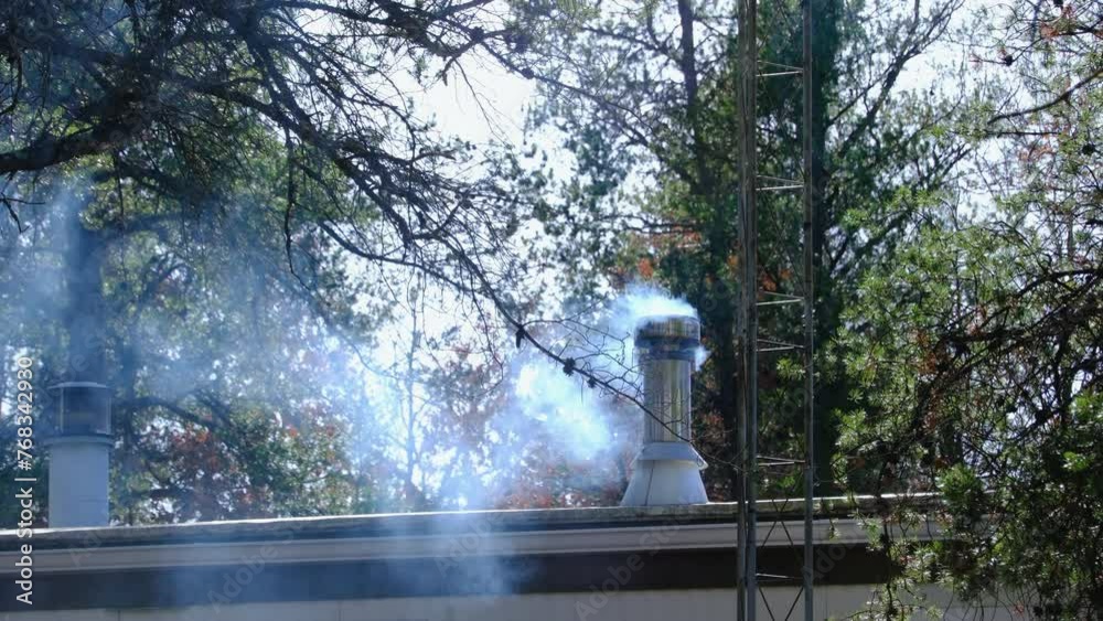 Smoke slowly rising and wafting from metal chimney while burning wood ...