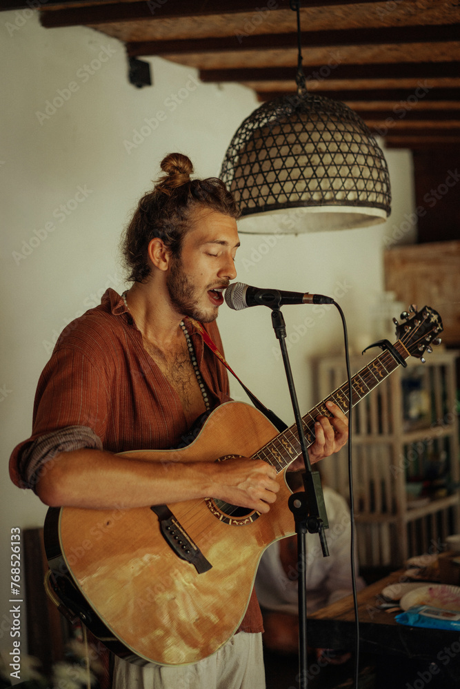 Young man musician plays the guitar and sings into a microphone. Stock ...
