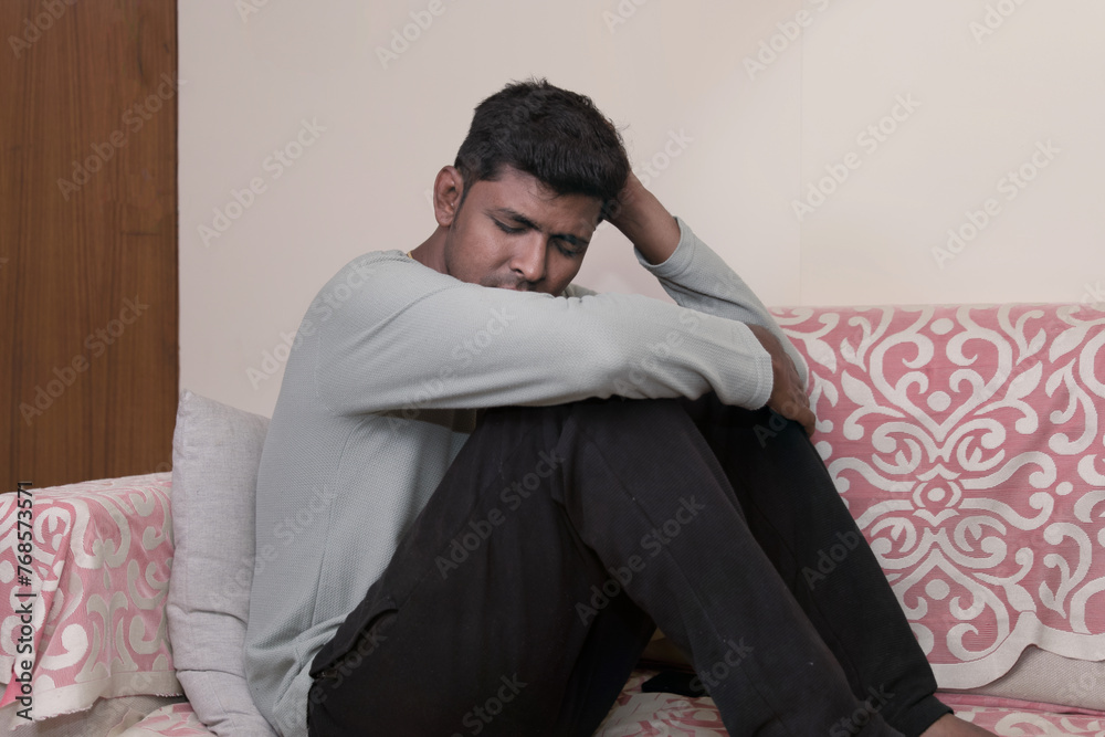 young sad and depressed indian man at home living room sofa feeling ...