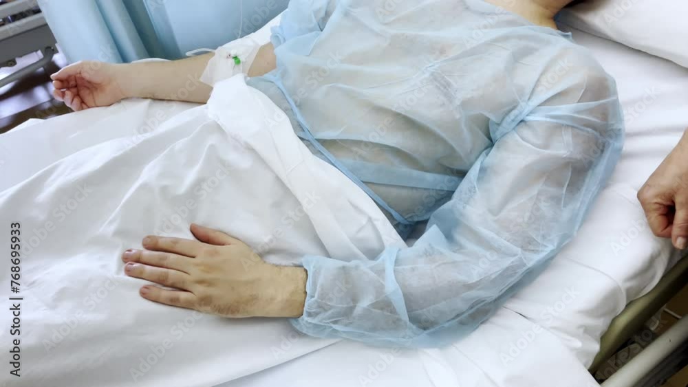 Sick male in sterile disposable surgical gown lying on hospital bed ...