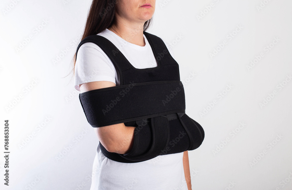 A girl in a medical brace on the shoulder joint for rehabilitation ...