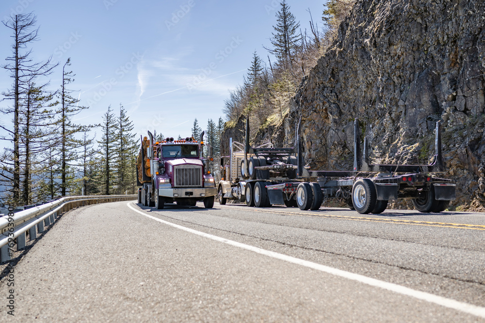 Two tree log carrier big rig semi trucks with semi trailers met on a ...