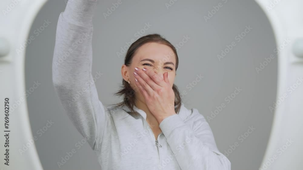 Confused woman opens toilet lid, looks through inside, grimaces at ...