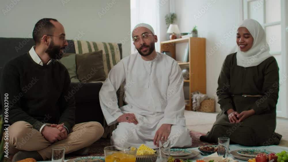 Young Muslim man in white kandora and skullcap talking to his twin ...