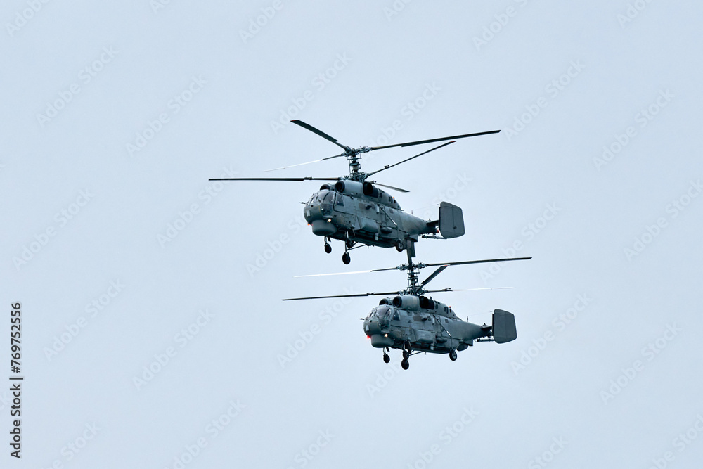 Two Russian military helicopters armed with missiles flies in blue sky ...