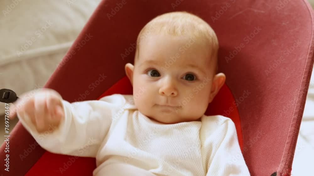 beautiful baby rocking in rocking chair swing and looking at camera and ...
