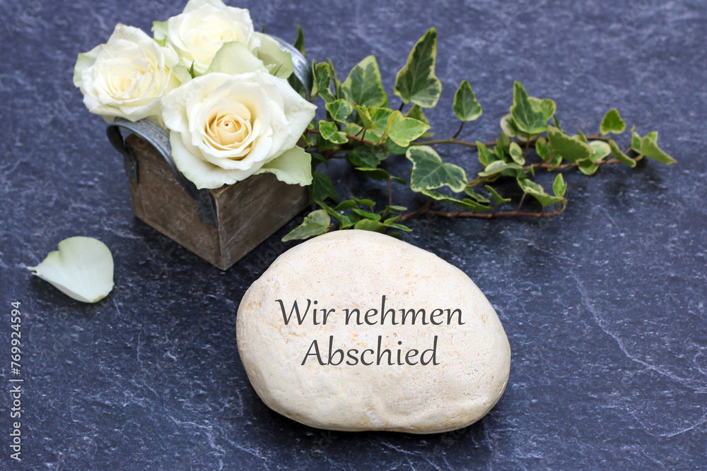 Weiße Rosen und ein Stein mit der Inschrift wir nehmen Abschied. Stock ...