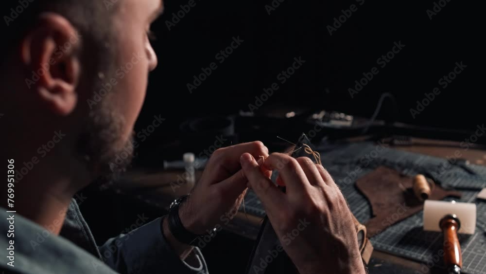 Tanner man uses wooden vise for leatherworking. Guy with a needle and ...