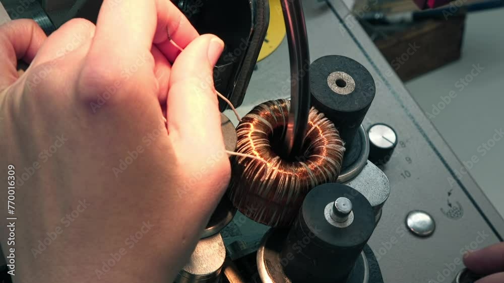 An engineer adding the copper wires into the coil machine. An engineer ...