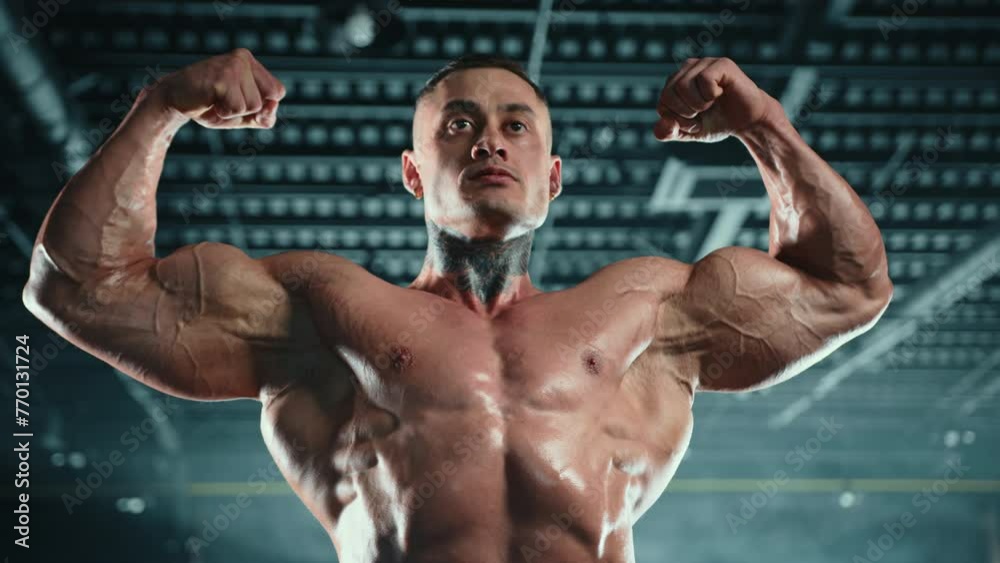 Vidéo Stock An impressively muscled bodybuilder flexes his biceps ...