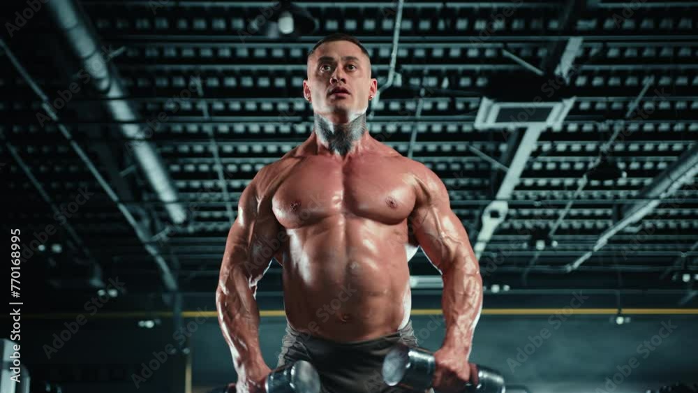 A muscular bodybuilder with intense focus performs dumbbell flyes in a ...