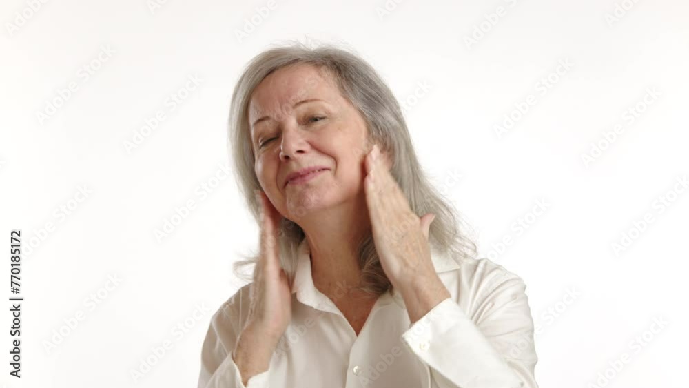 Gracious senior lady lovingly admires her reflection, gently touching ...