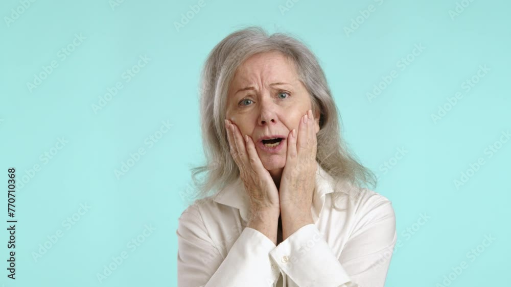 A radiant elderly lady laughs heartily with her hands on her cheeks ...