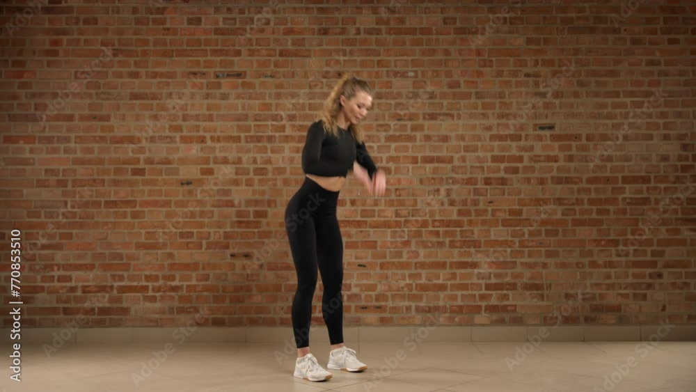A fitness trainer in a black attire stretches arms to the sky with ...