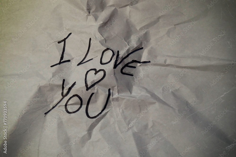 crumpled sheet of paper, with the writing, "I love you", crossed out ...