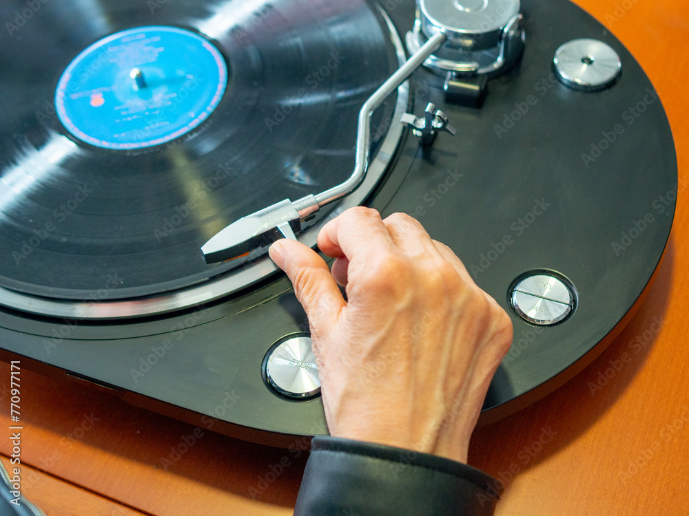 Lady hand holding the tonearm of her turntable ready to play a vinyl ...