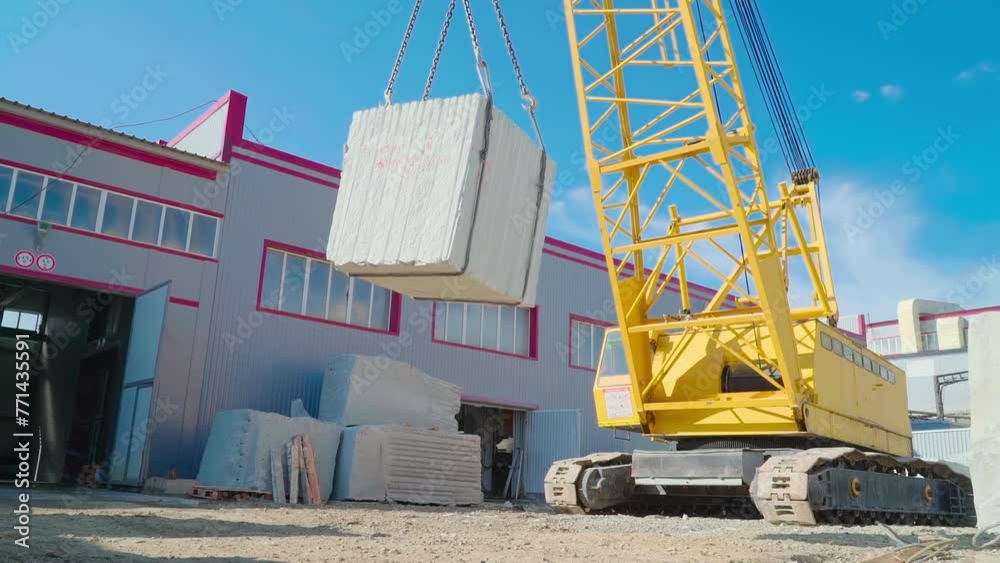 Modern crane is moving big granite stones in the factory backyard. Huge ...