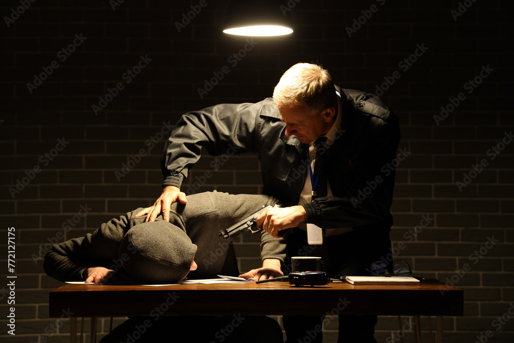 Mature FBI agent threatening suspect with gun in interrogation room ...