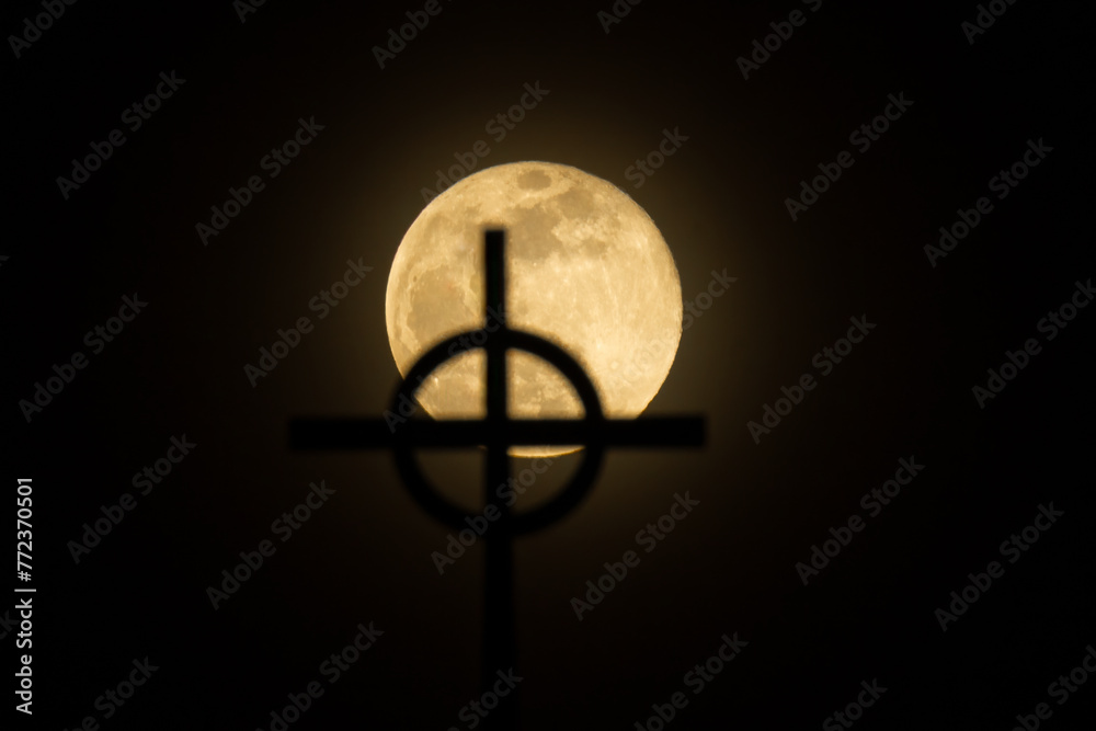 Cross and Moon. A full moon rises over a Christian Cross of a steeple ...