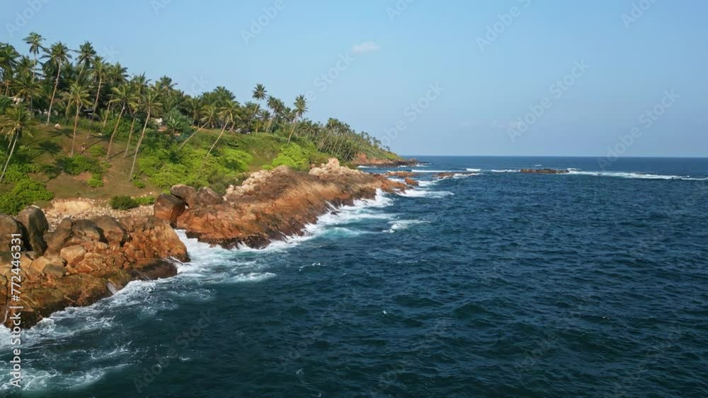 Aerial view captures waves colliding with craggy coastline amidst lush ...