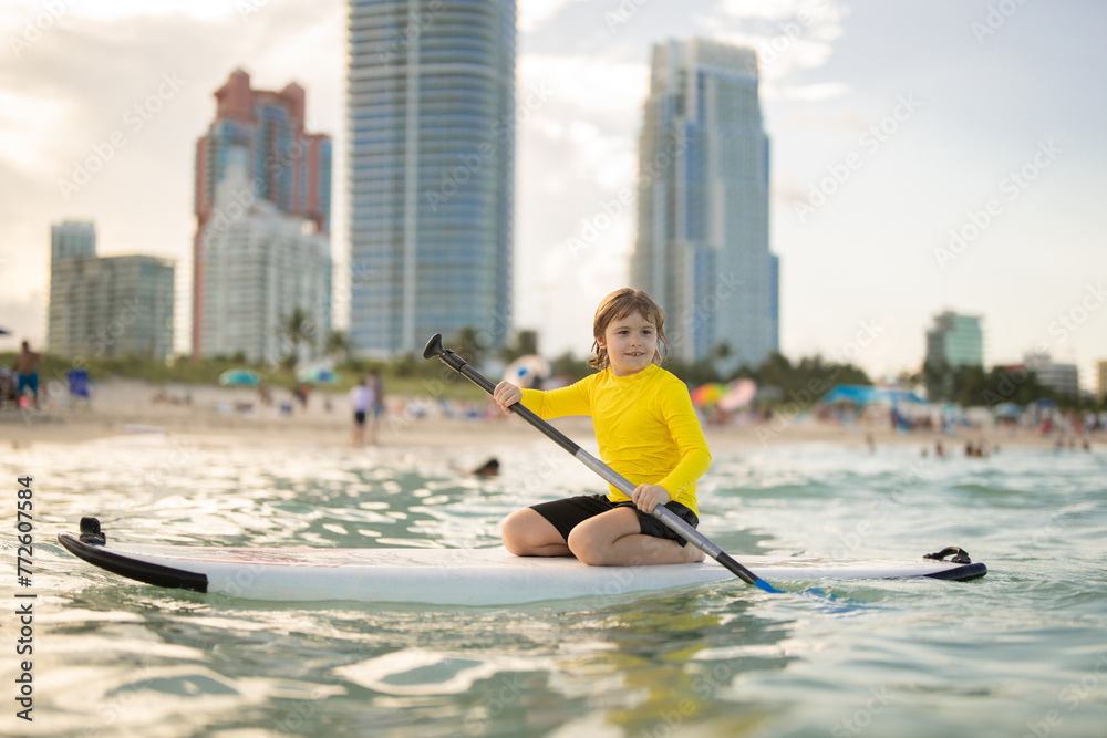 Kid riding on a paddle board. Summer holidays. Kid paddle surf surfer ...