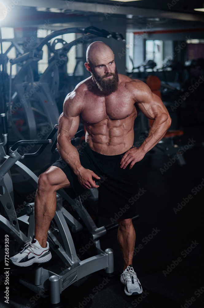 Muscular bald man posing in shorts. Bodybuilder showing off his shape ...