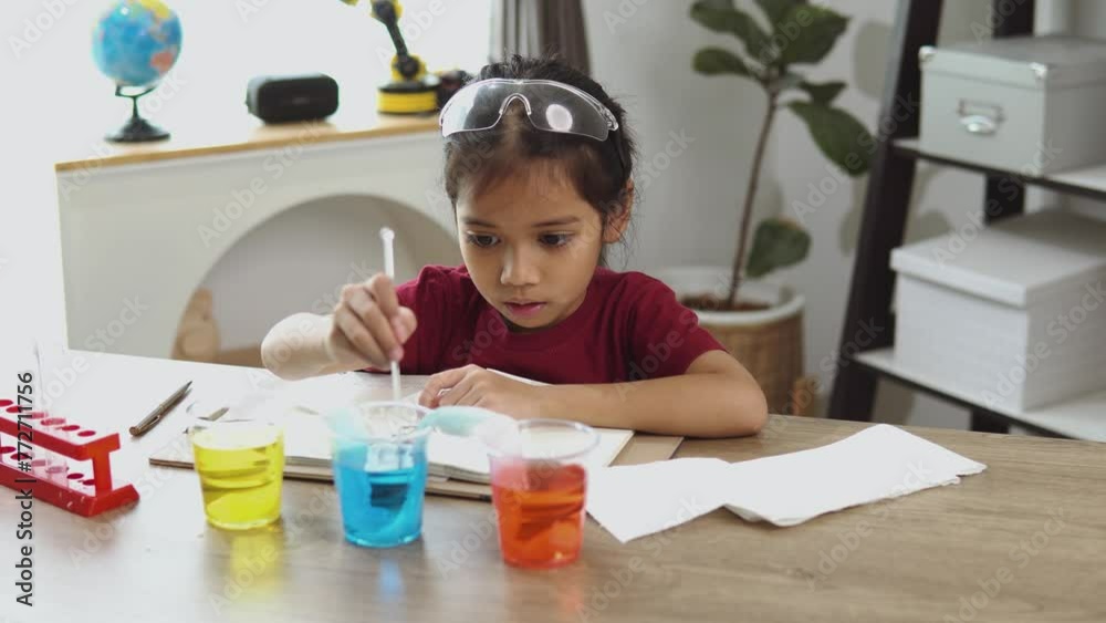 Cute little Asian girl is experimenting or learning science at home ...