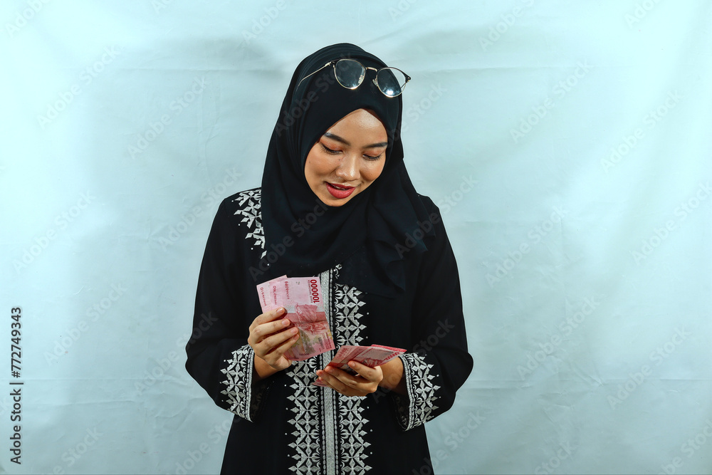 exited beautiful young Asian Muslim woman wearing hijab counting cash ...
