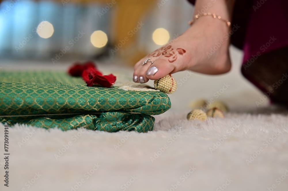 Toes of indian bride in Saptapadi Ceremony. Flowers, betel nut and rice ...