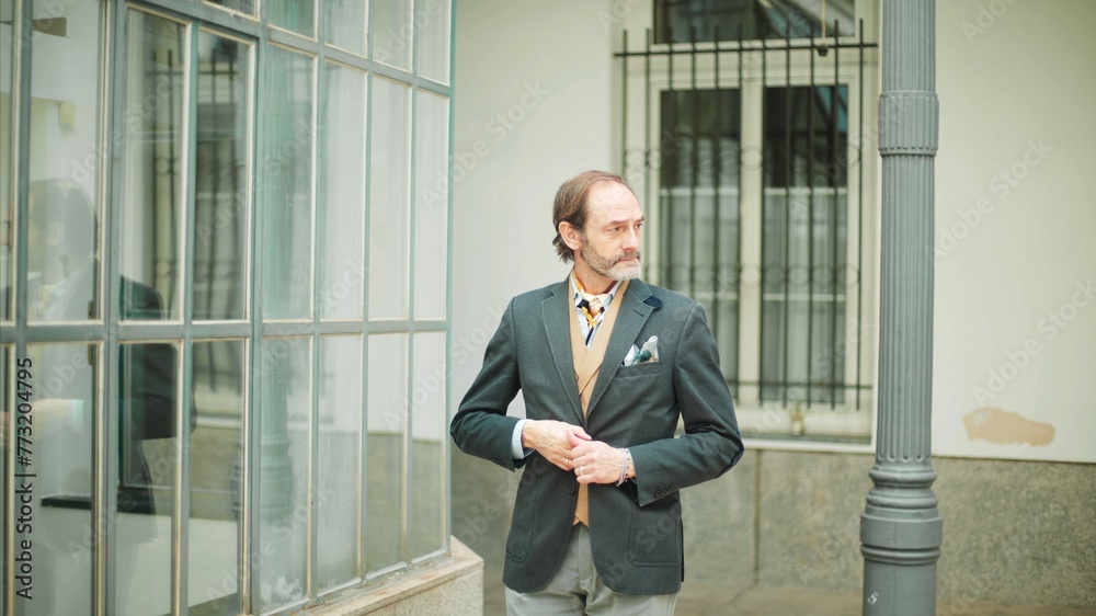 Refined man buttoning jacket near urban glass facade. Stock Photo ...