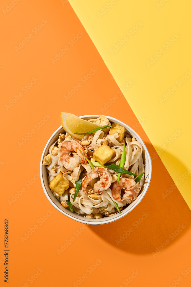 Asian street food - pad thai noodles with shrimp on coloured background ...