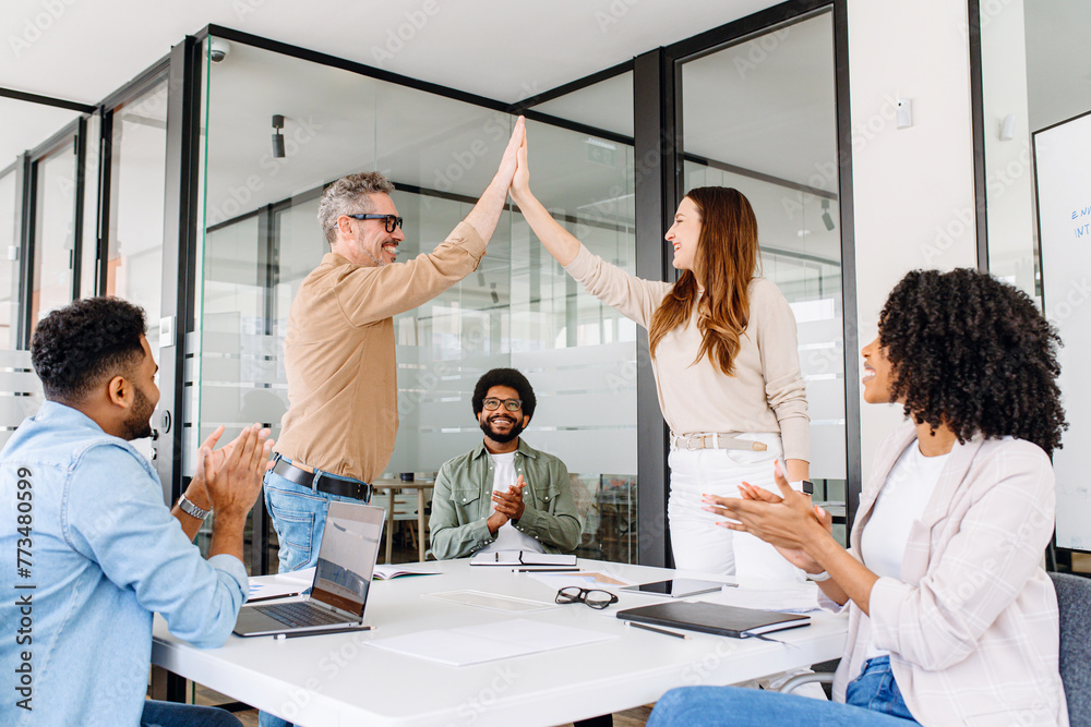 In a spirited office atmosphere, colleagues share a high-five ... In a spirited office atmosphere, colleagues share a high-five ...