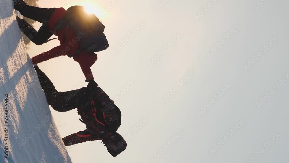 teamwork concept. help your partner climb snowy mountain with backpack. hiking winter mountains ...