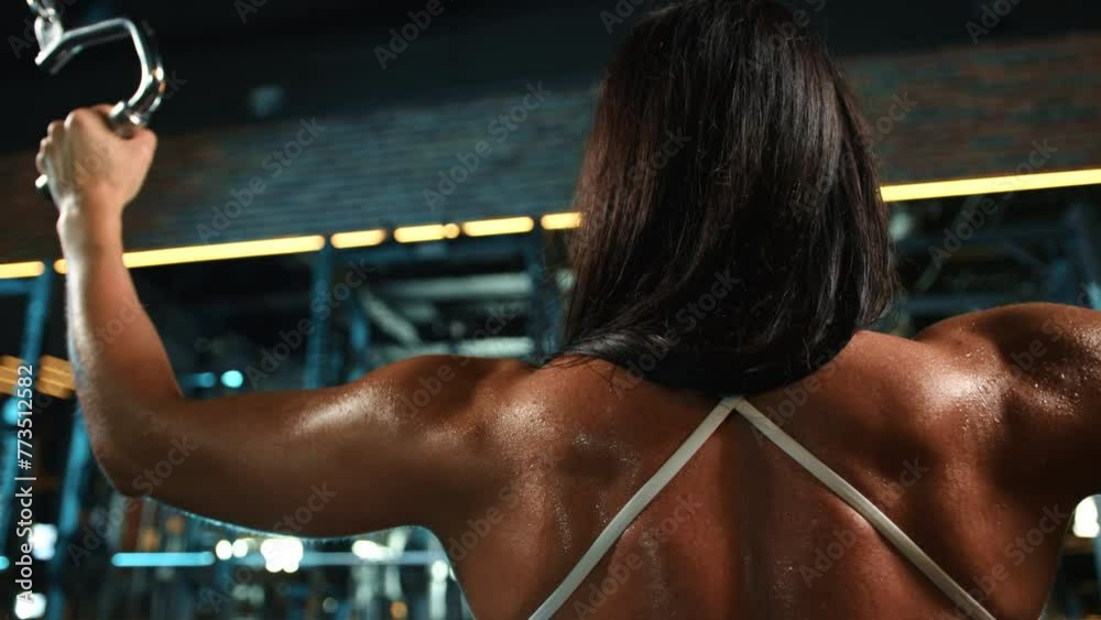 Close-up of a female athlete's back as she exercises on a crossover ...