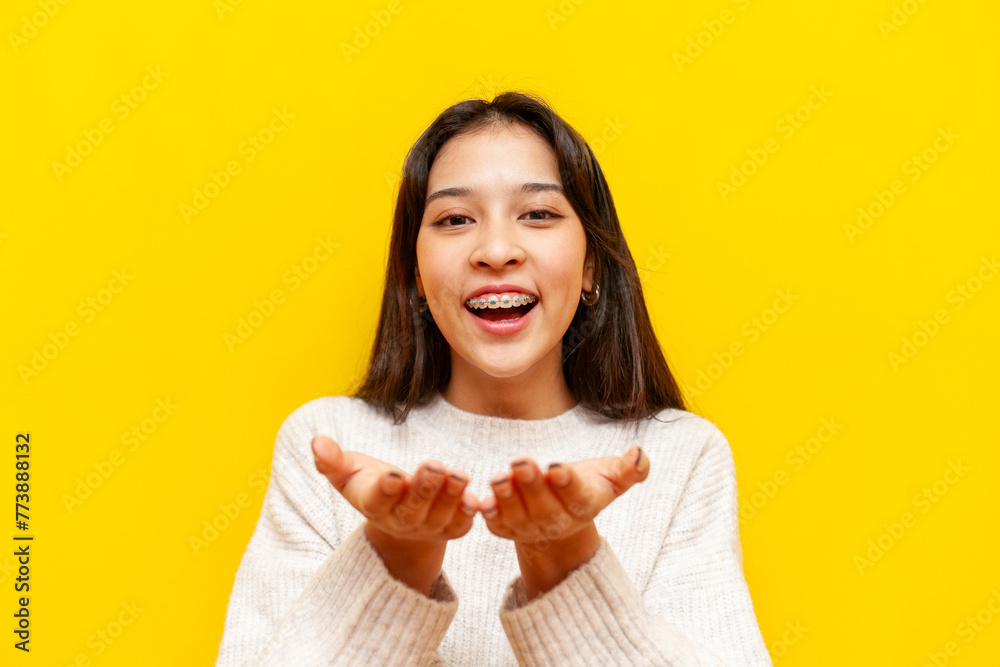 young cheerful asian woman with braces begging and holding empty hands ...
