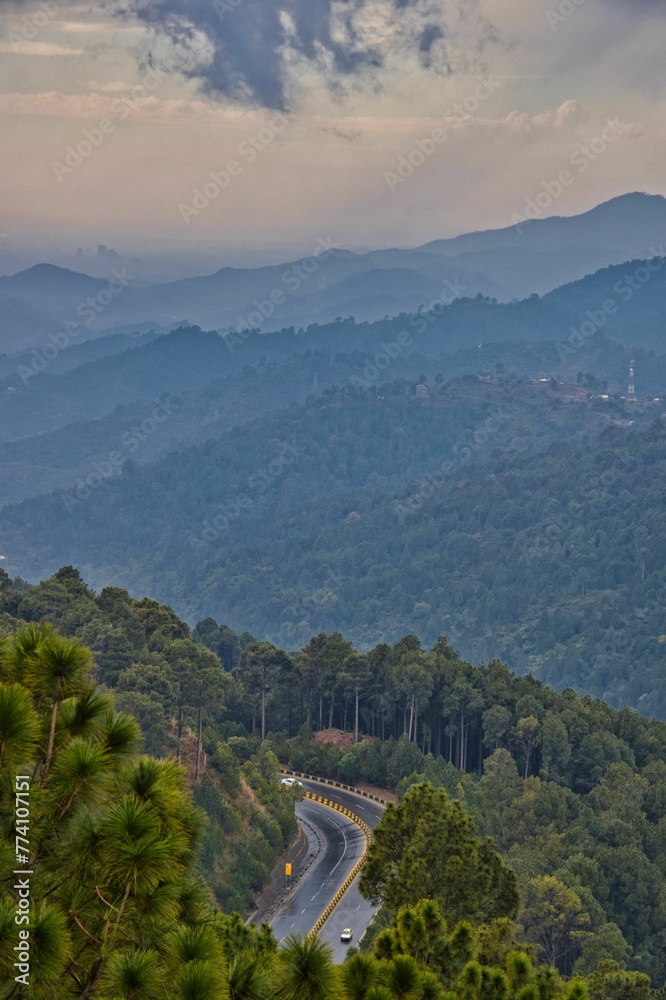Vertical shot of the Murree Expressway on the mountain covered in trees ...