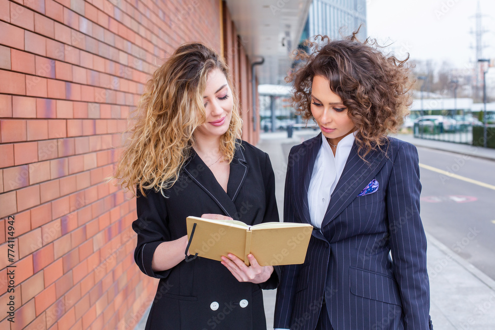 Two successful business women are talking in the city in front of a ...