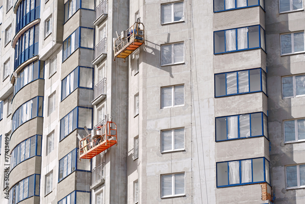 Construction facade, window sill installation. Workers using lift ...