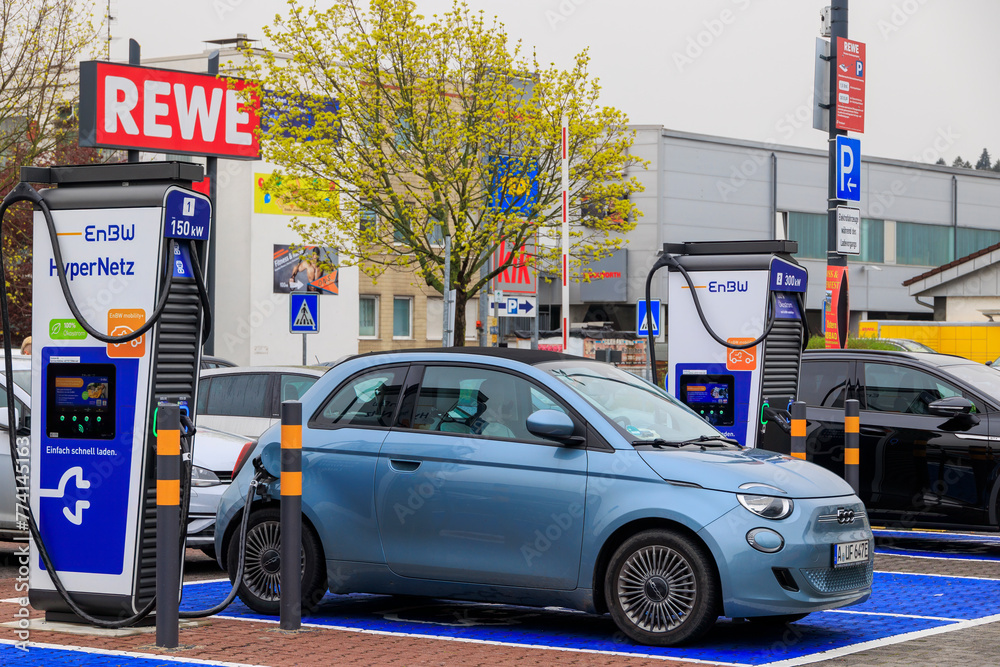 Blue Fiat 500e convertible in a Rewe car park at an ENBW fast charging ...
