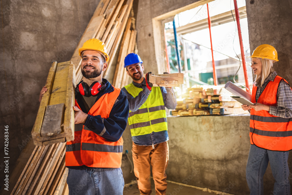 Two construction workers carrying a scaffolding at a building stie ...