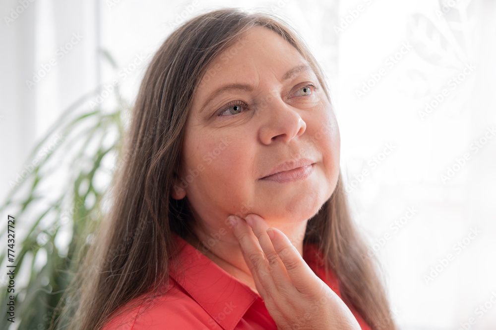 mature woman touches aging face, focusing on wrinkles, sagging and ...
