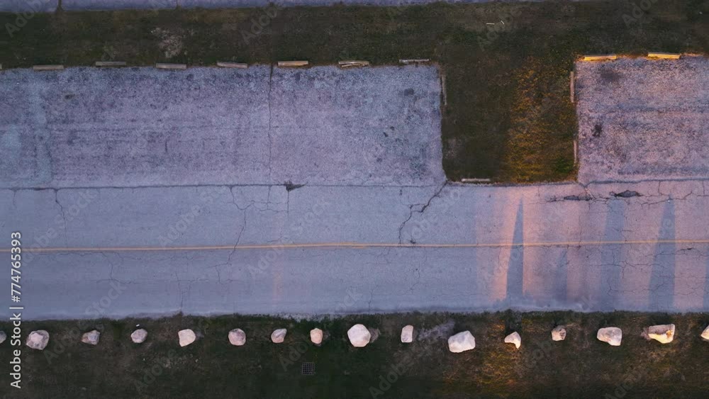 Drone top down pan across empty old parking lot with long shadows from ...