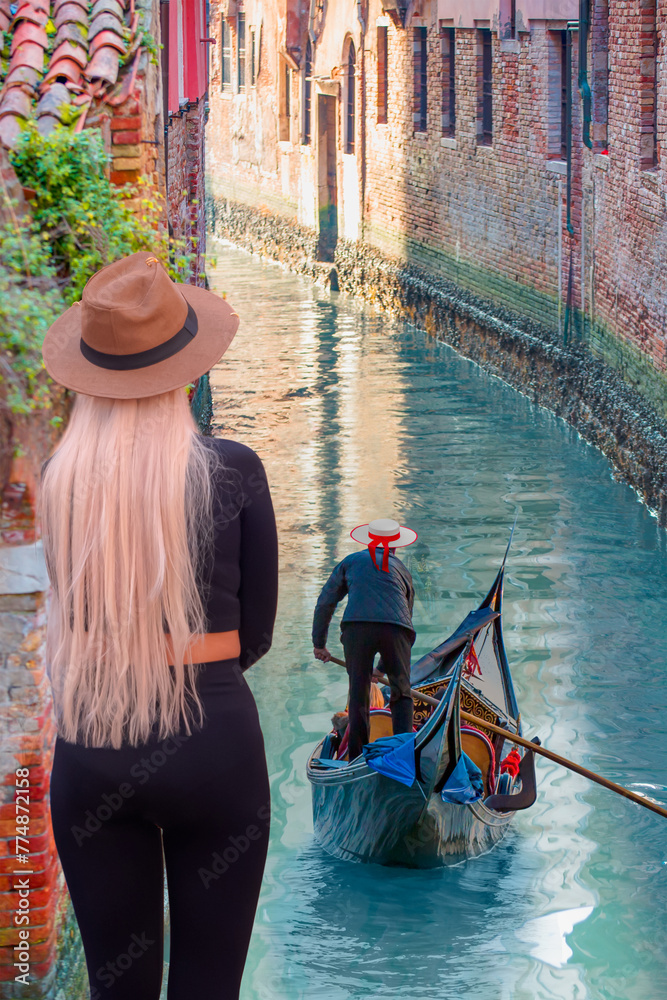 A stylish blonde woman on the bridge watching the Venetian gondolier ...