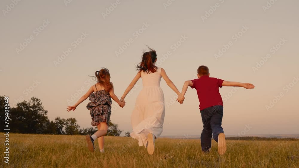 mother runs into sunset holding her son daughter hand, happy family ...
