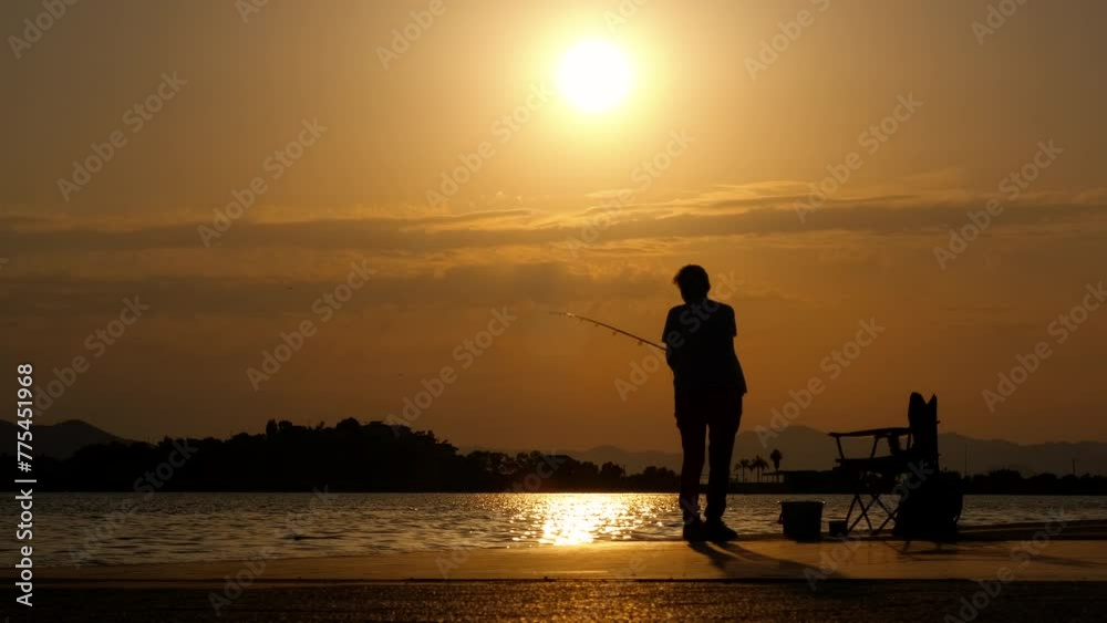 Leisure time with fishing on evening bay. A silhouette of female with ...